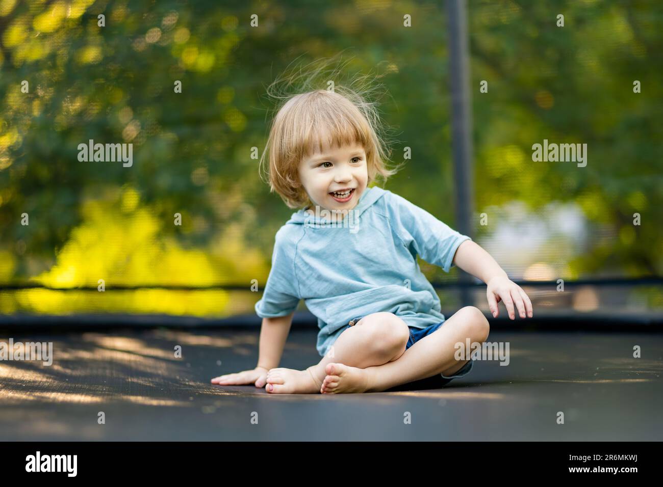 Cute toddler boy jumping on a trampoline in a backyard on warm and ...