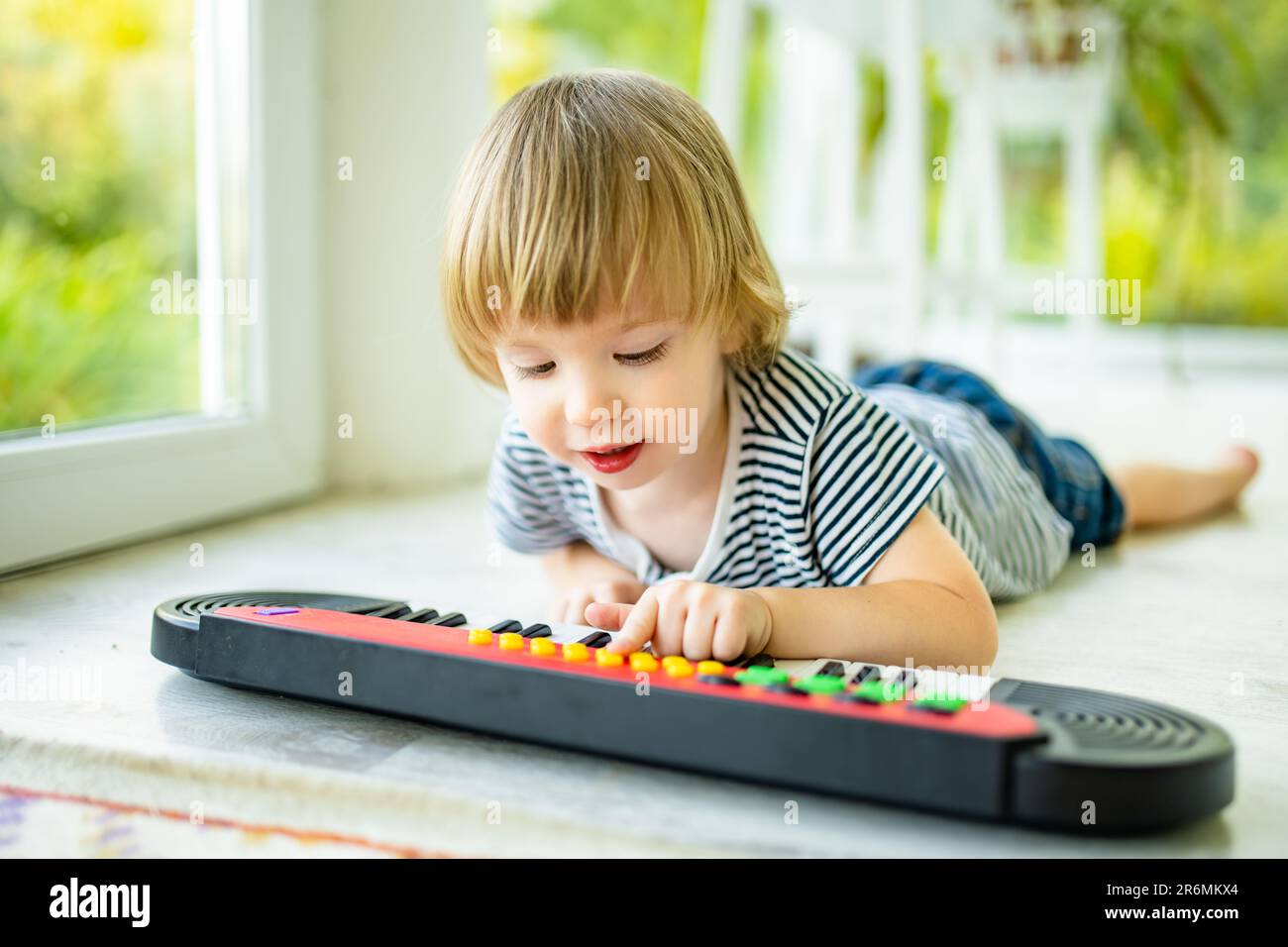 Funny toddler boy playing toy piano at home. Little boy learning to ...