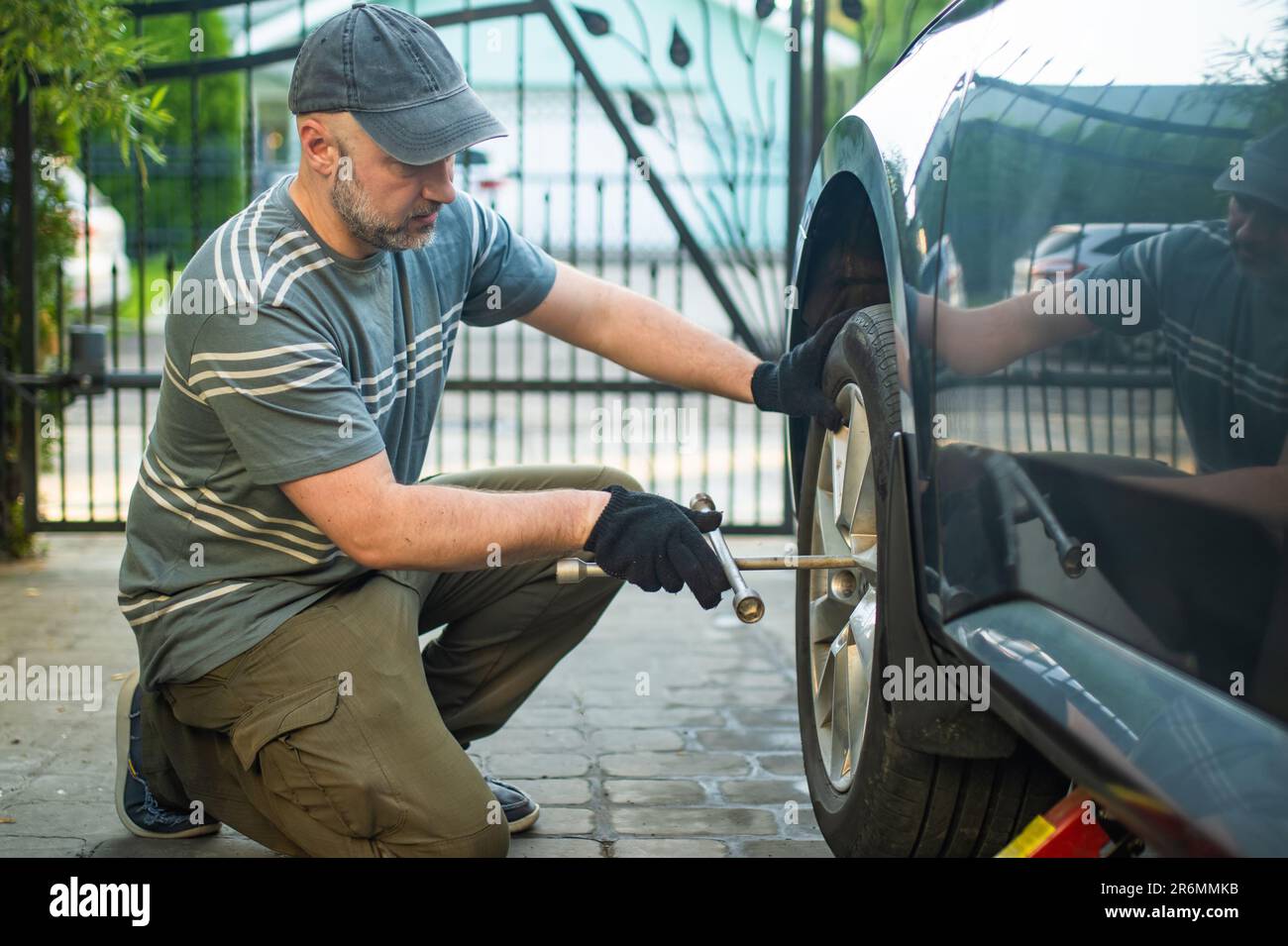 Man changing car wheels at his backyard. Technician using tools to fix ...