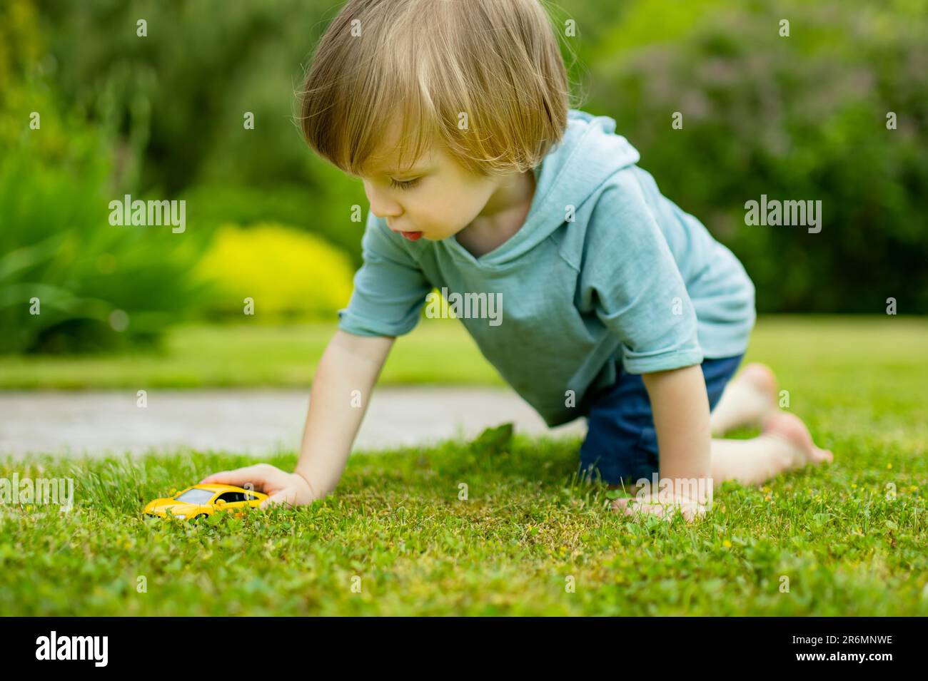 Cute toddler boy playing with yellow toy car outdoors. Kid exploring ...