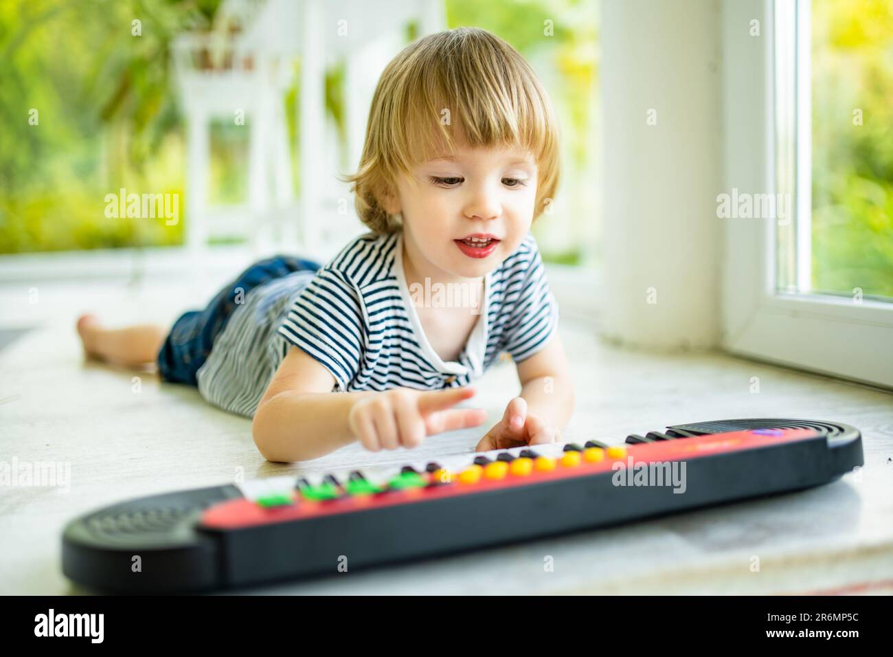 Funny toddler boy playing toy piano at home. Little boy learning to ...