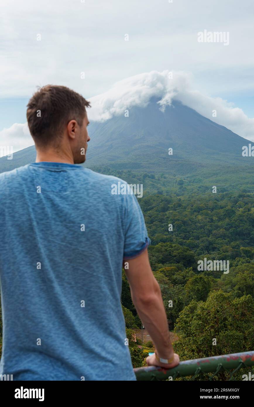 Male hiker looking out at the Arenal volcano in Costa Rica Stock Photo ...