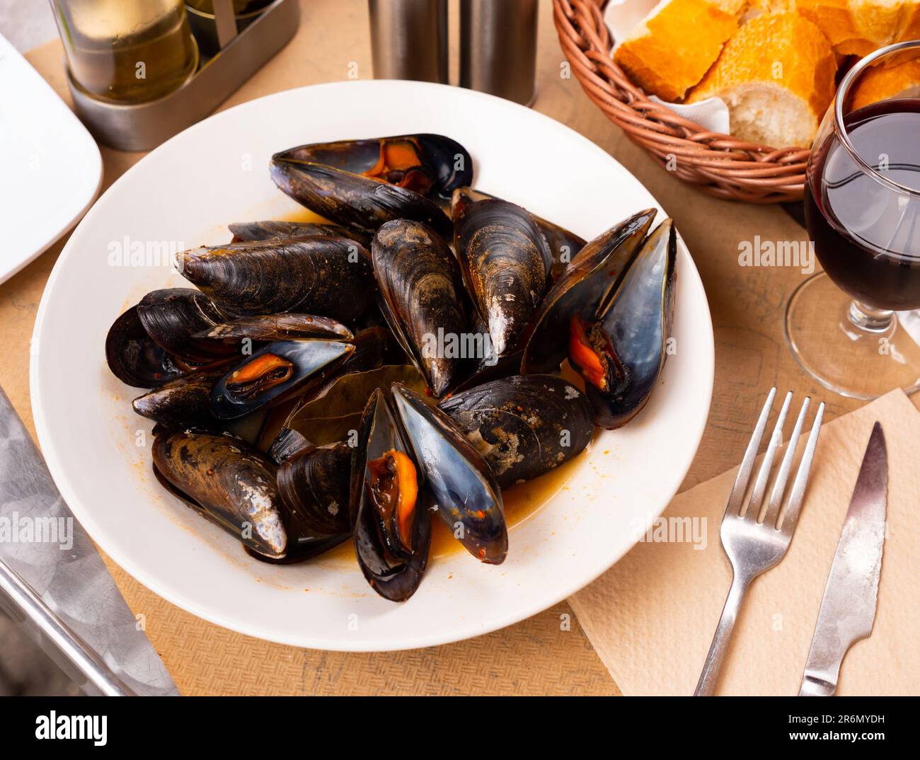 Portion of steamed mussels served with bay leaf on plate. Spanish dish ...