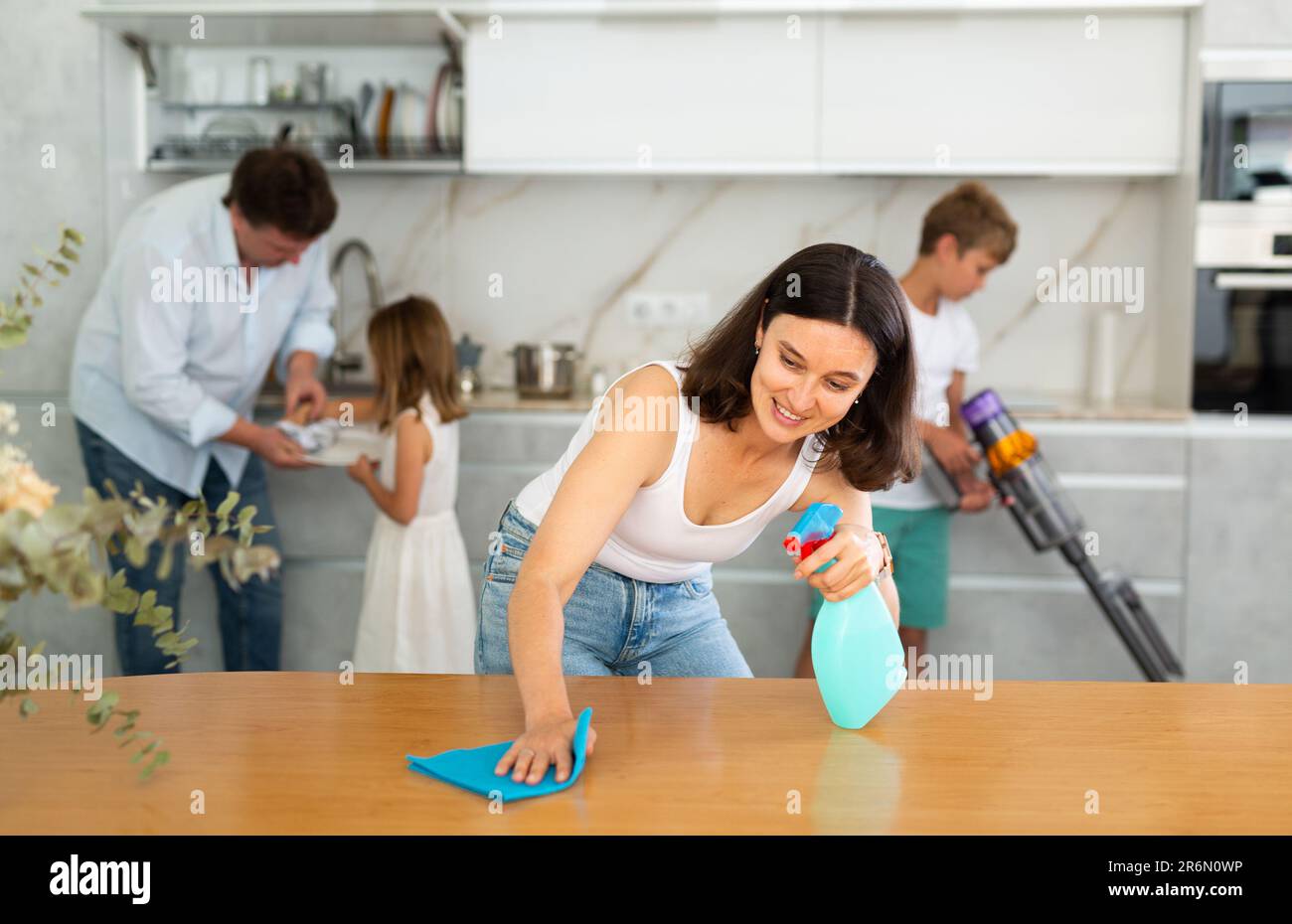 Happy family with two children doing cleaning in kitchen Stock Photo ...