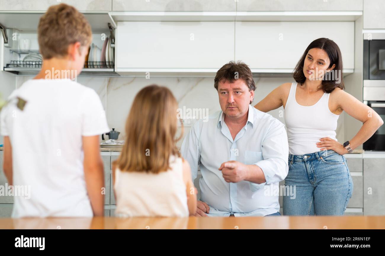 Angry parents scolding two children standing in front of them Stock ...