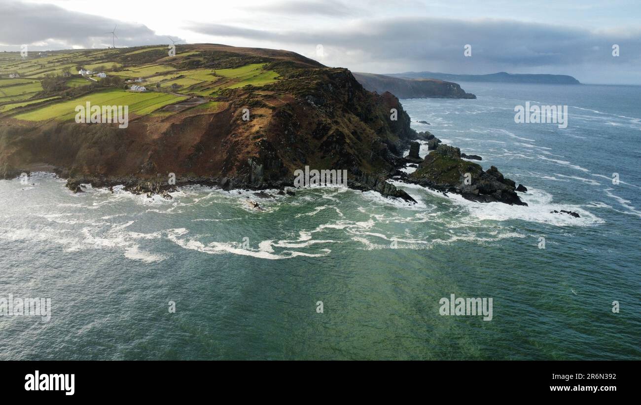 A majestic scene of towering cliffs and lush green fields near the ...