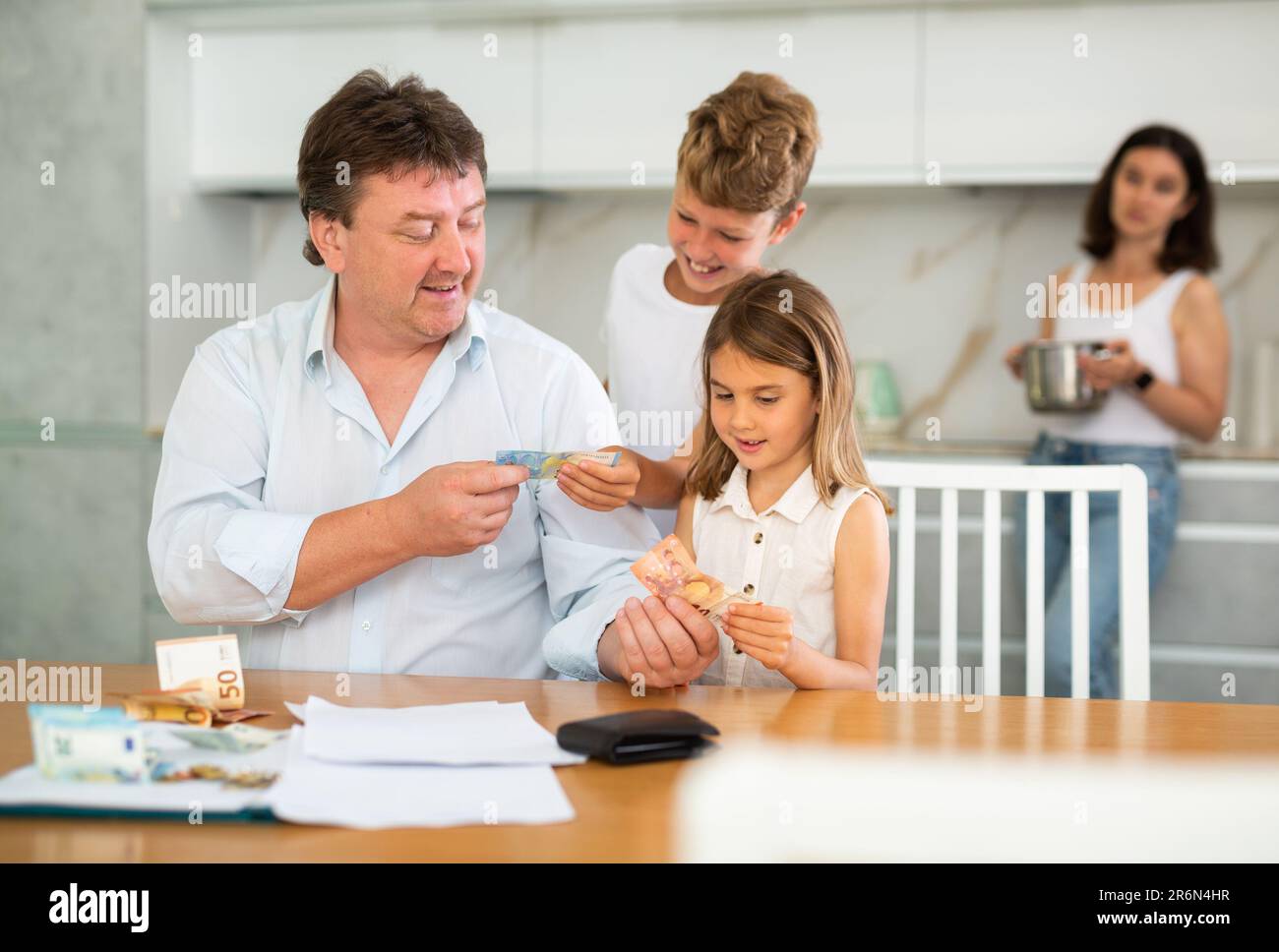 Happy father giving money to children in the kitchen Stock Photo - Alamy