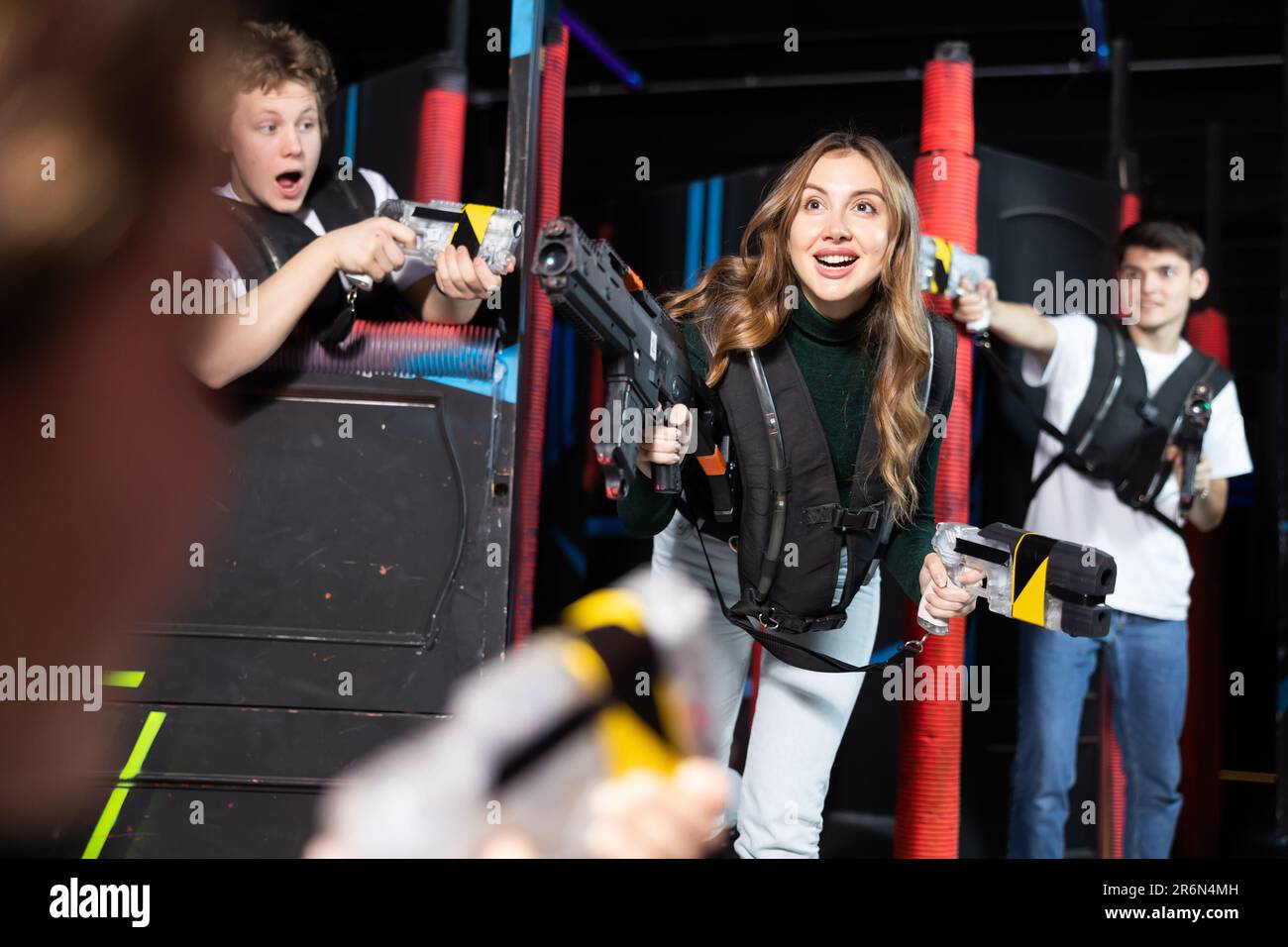 Laughing players mens and womens playing in teams in dark laser tag ...