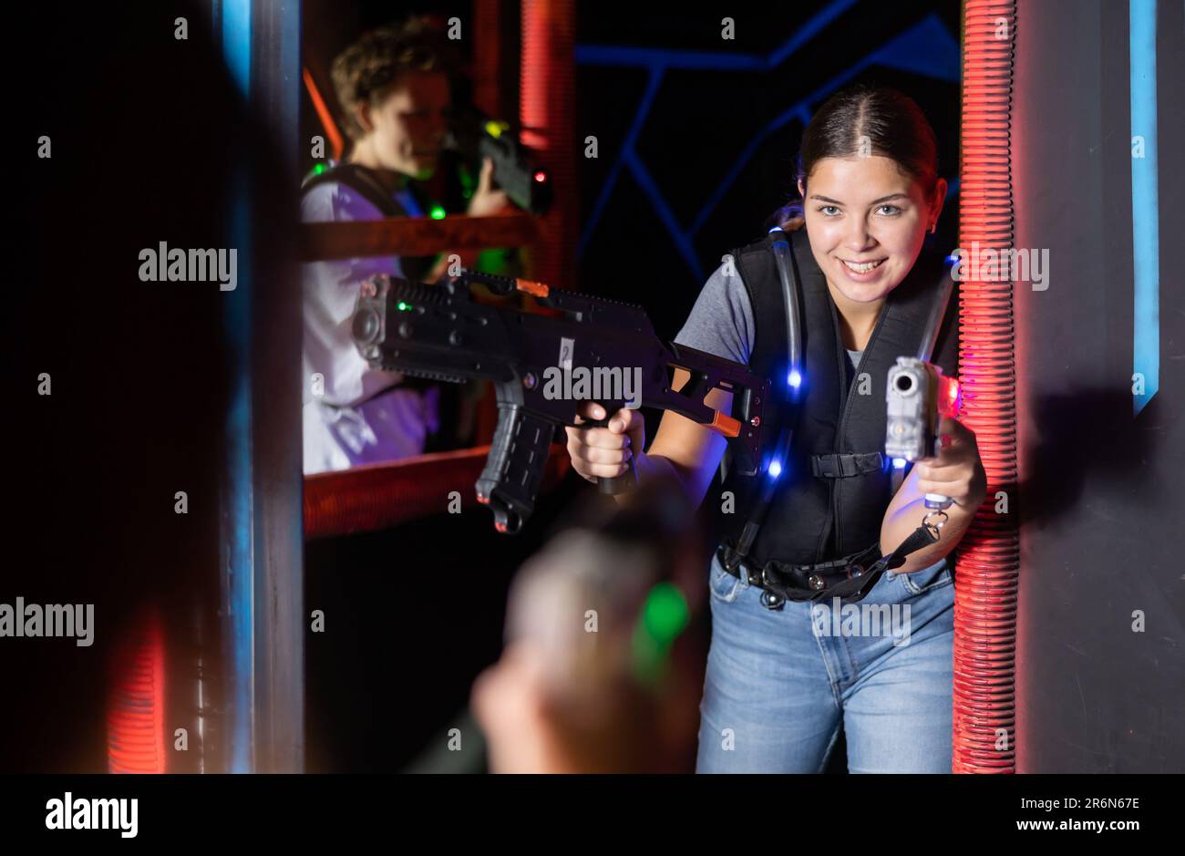 Smiling girl with laser pistol during playing laser tag with her ...