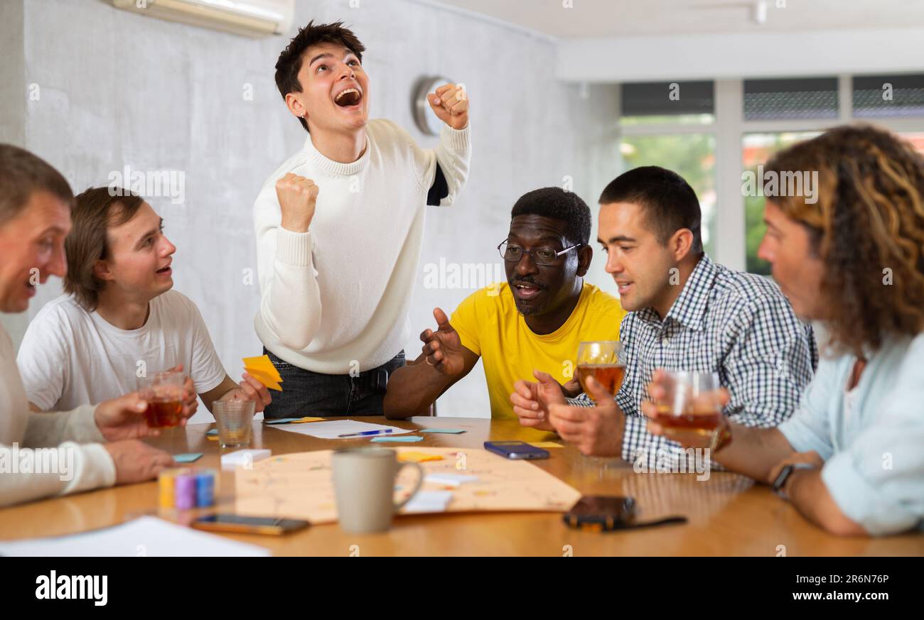 Cheerful guy playing board game with male friends Stock Photo - Alamy