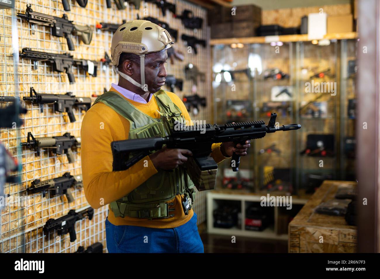 Man in armor vest selecting machine gun in weapon shop Stock Photo - Alamy