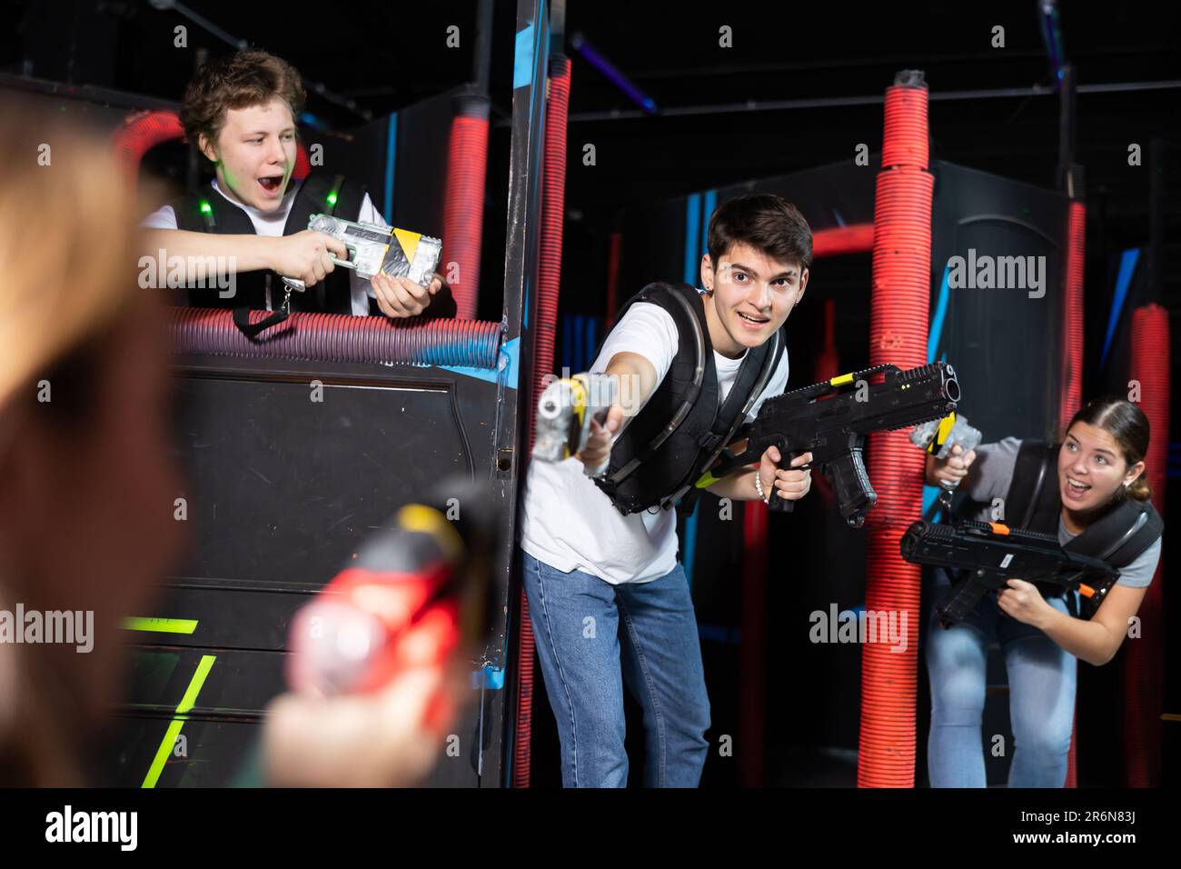 Laughing players mens and womens playing in teams in dark laser tag ...