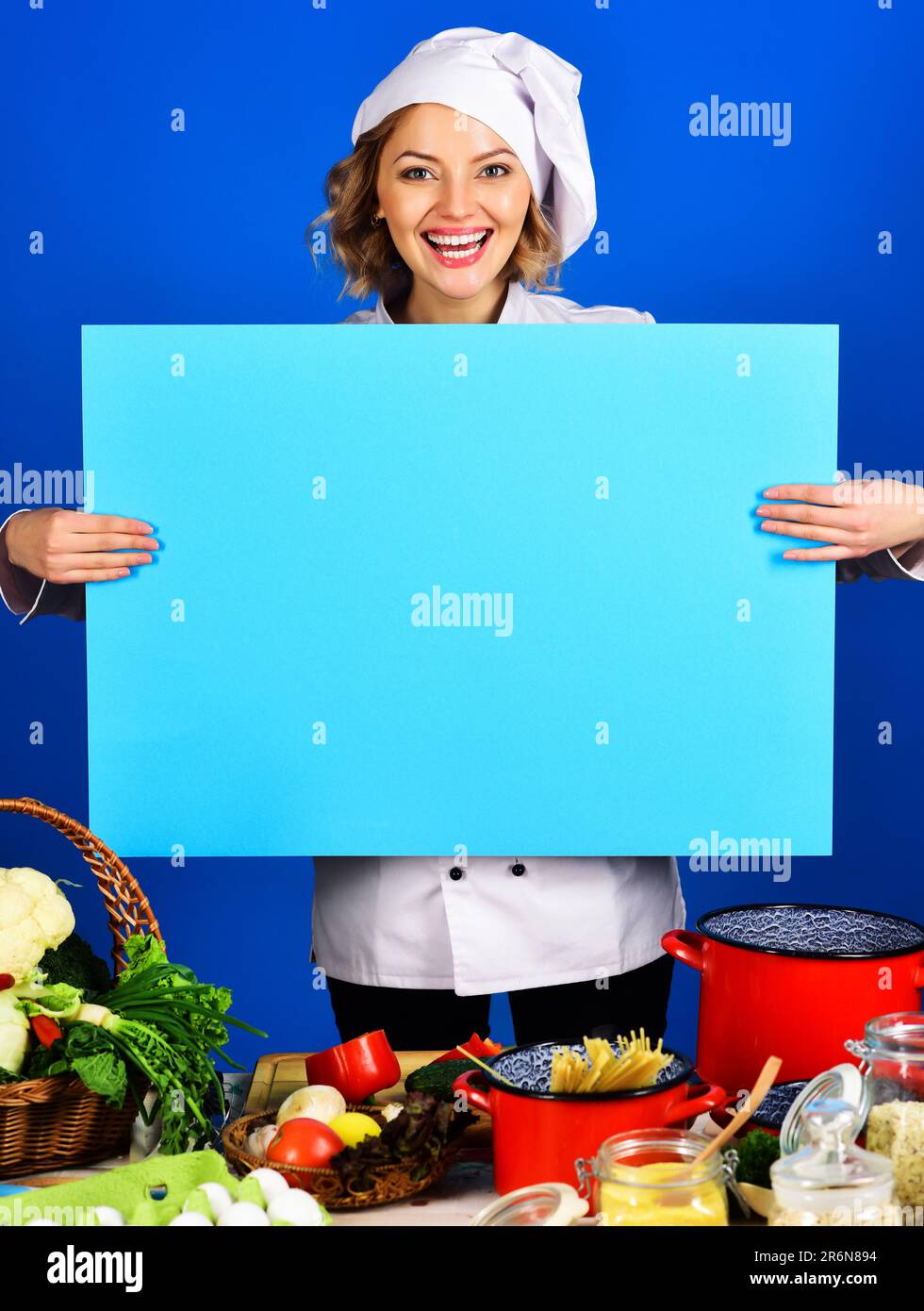 Smiling female chef cook with blank board. Food preparation. Healthy ...