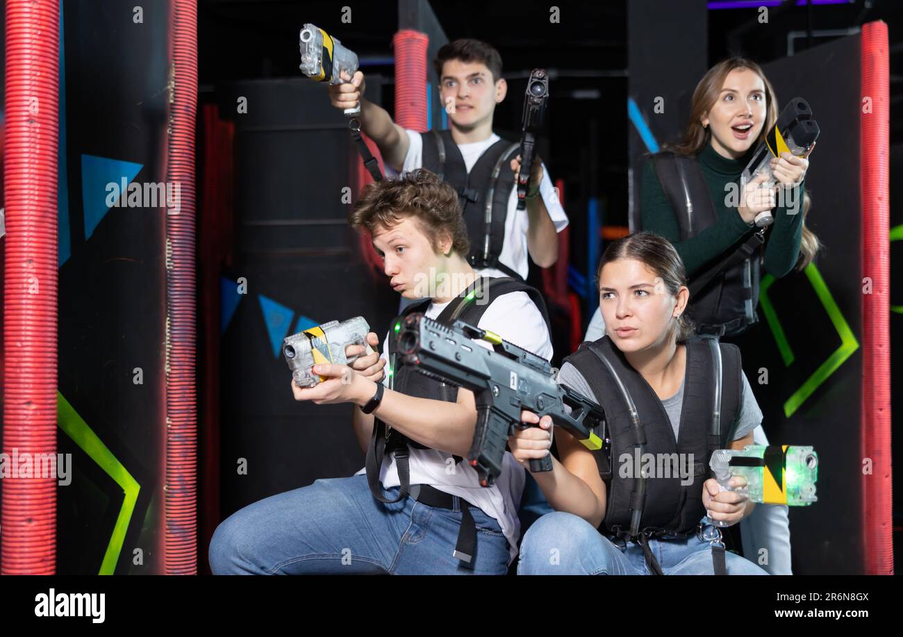 Girls and guys playing laser tag game opposite each other in modern ...