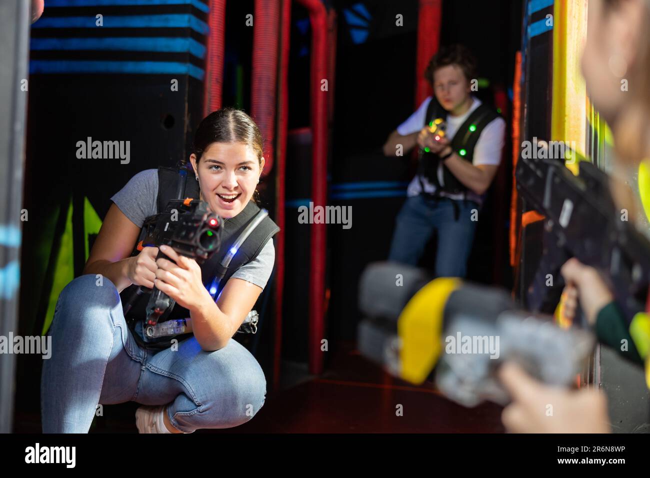 Positive girl holding laser pistol playing laser tag game with friends Stock Photo - Alamy