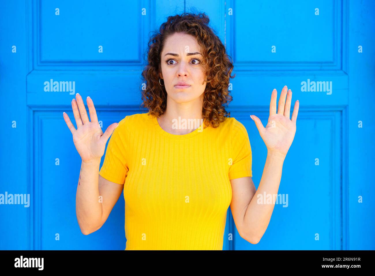 Scared woman with hands up on blue background Stock Photo - Alamy