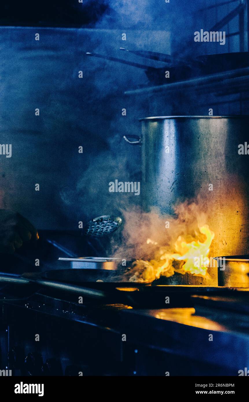 A modern kitchen with a frying pan with flames on the stovetop Stock ...