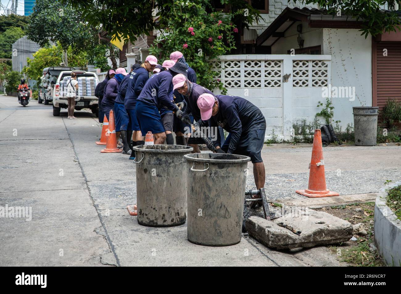 A team of Thai prisoners seen pulling up a rope from a public sewer to ...