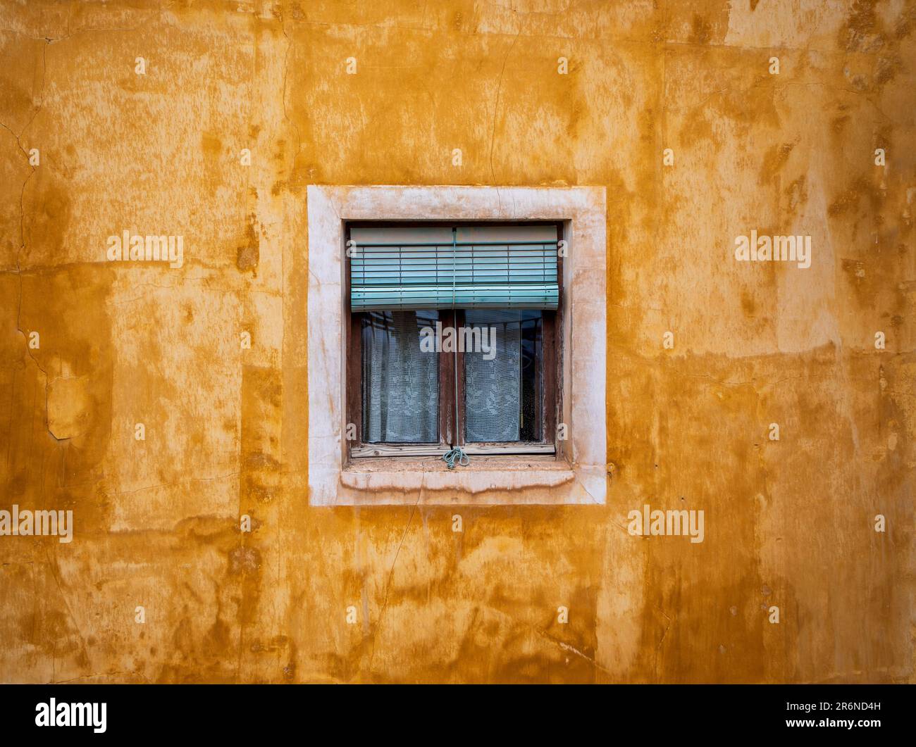 Detail of a yellow building facade, square homey window with green ...