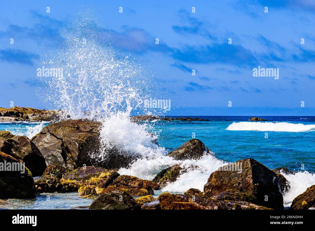 A scenic beach scene featuring a rocky shoreline with blue waters in ...