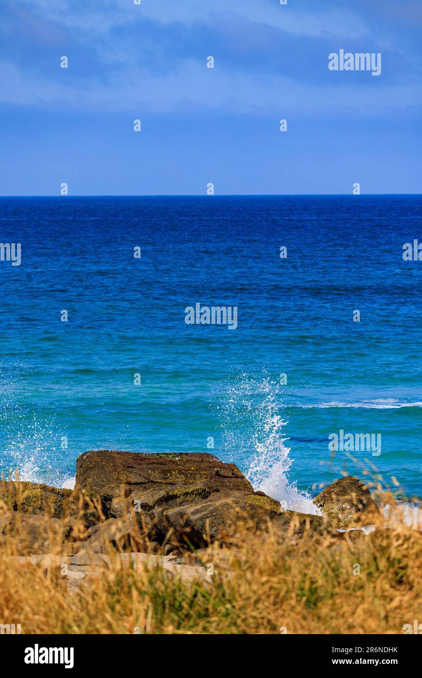 A scenic beach scene featuring a rocky shoreline with blue waters in ...