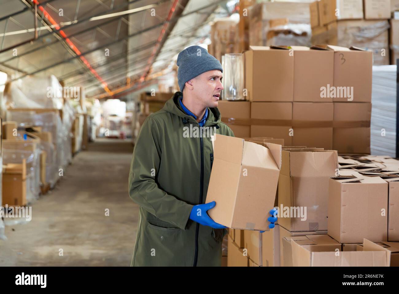 Warehouse worker carrying large box of goods in arehouse Stock Photo ...