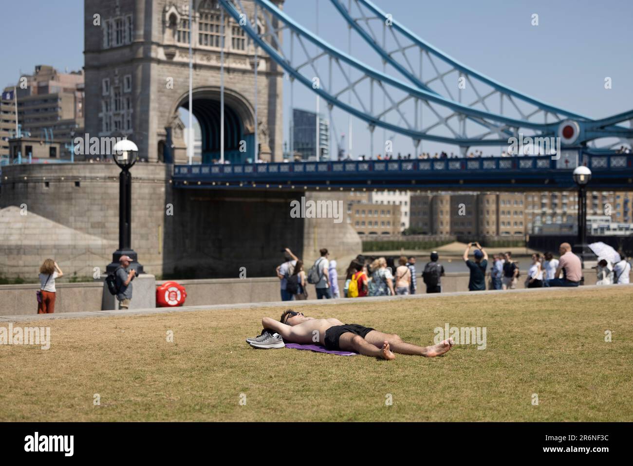 London, UK. 10th June, 2023. People are seen sunbathing at Tower Bridge ...
