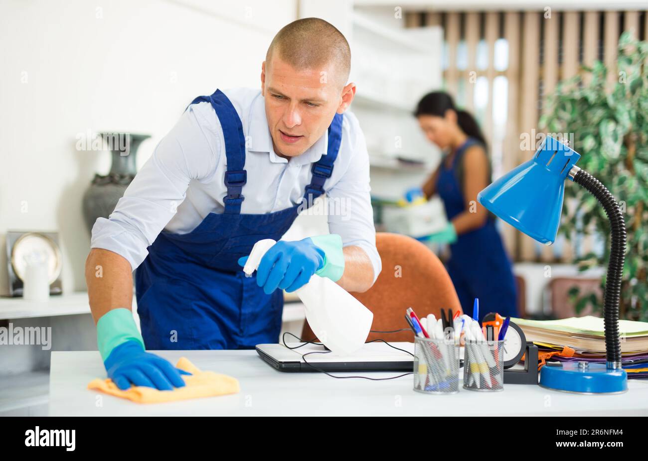 Man from cleaning service wiping office table Stock Photo - Alamy