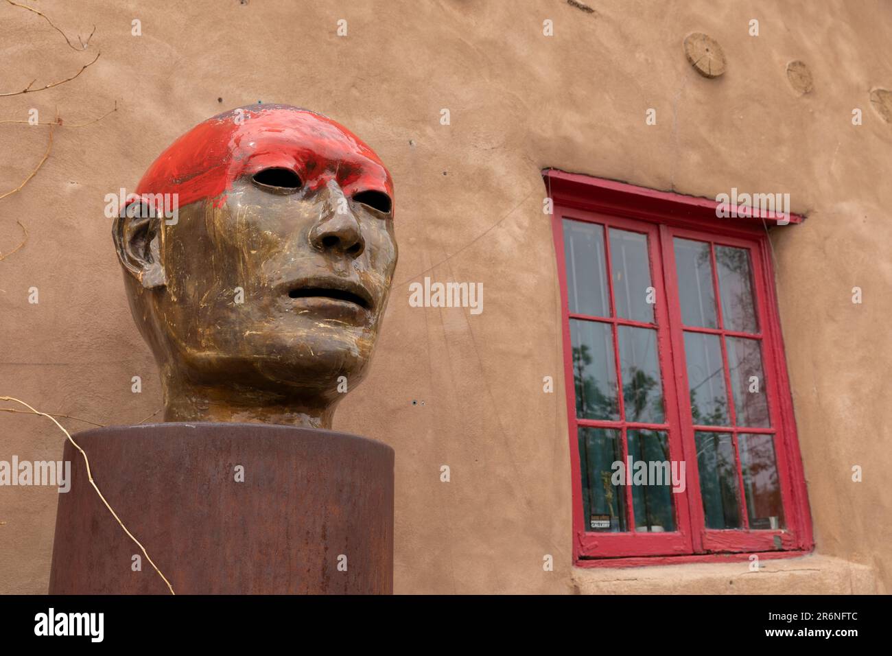 A modern sculpture of a human head dominates the adobe facade of the ...