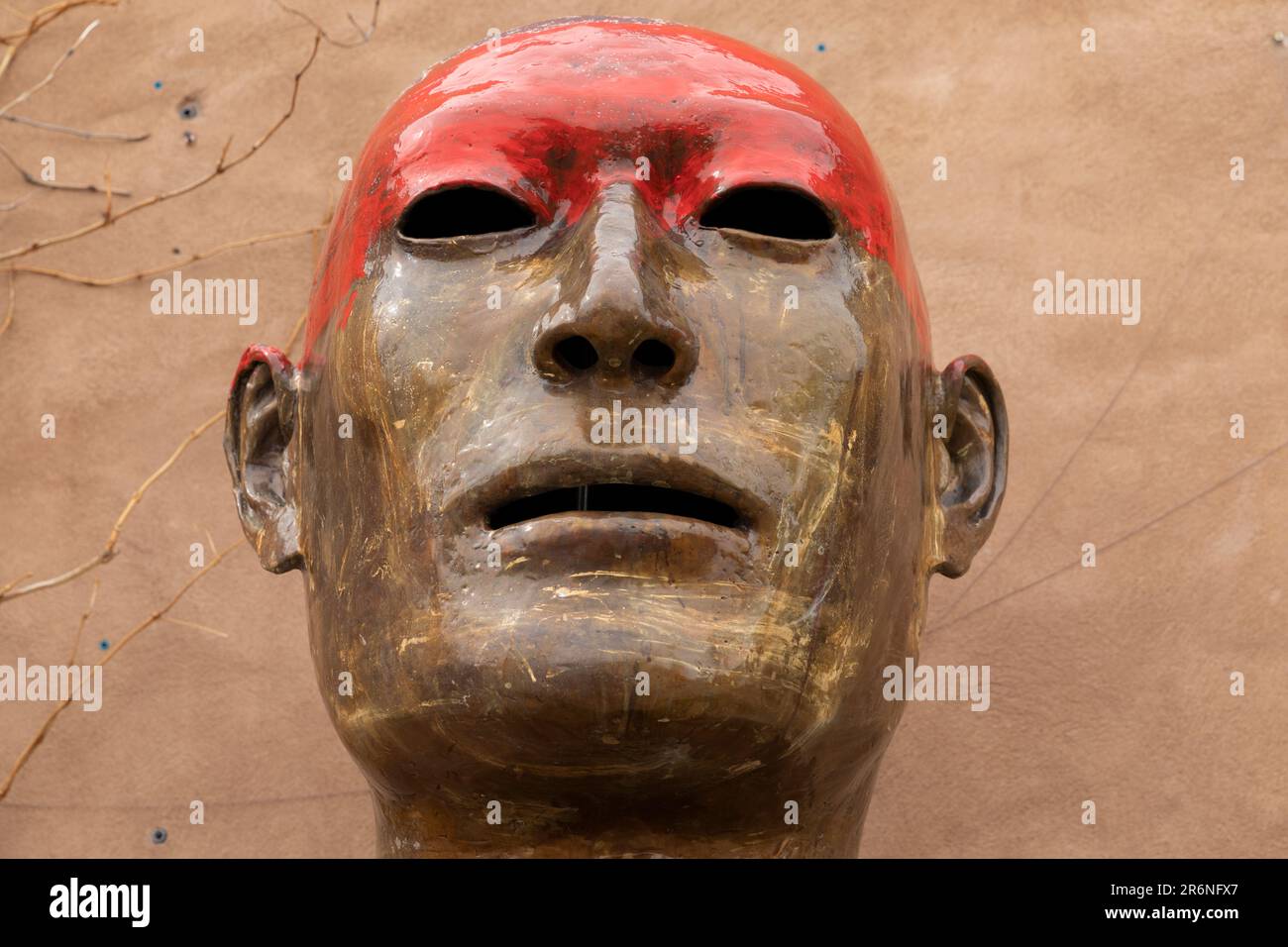 A modern sculpture of a human head dominates the adobe facade of the ...