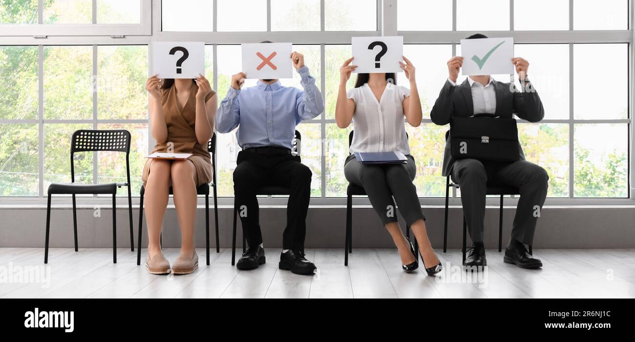 Young people hiding faces behind paper sheets while waiting for job ...