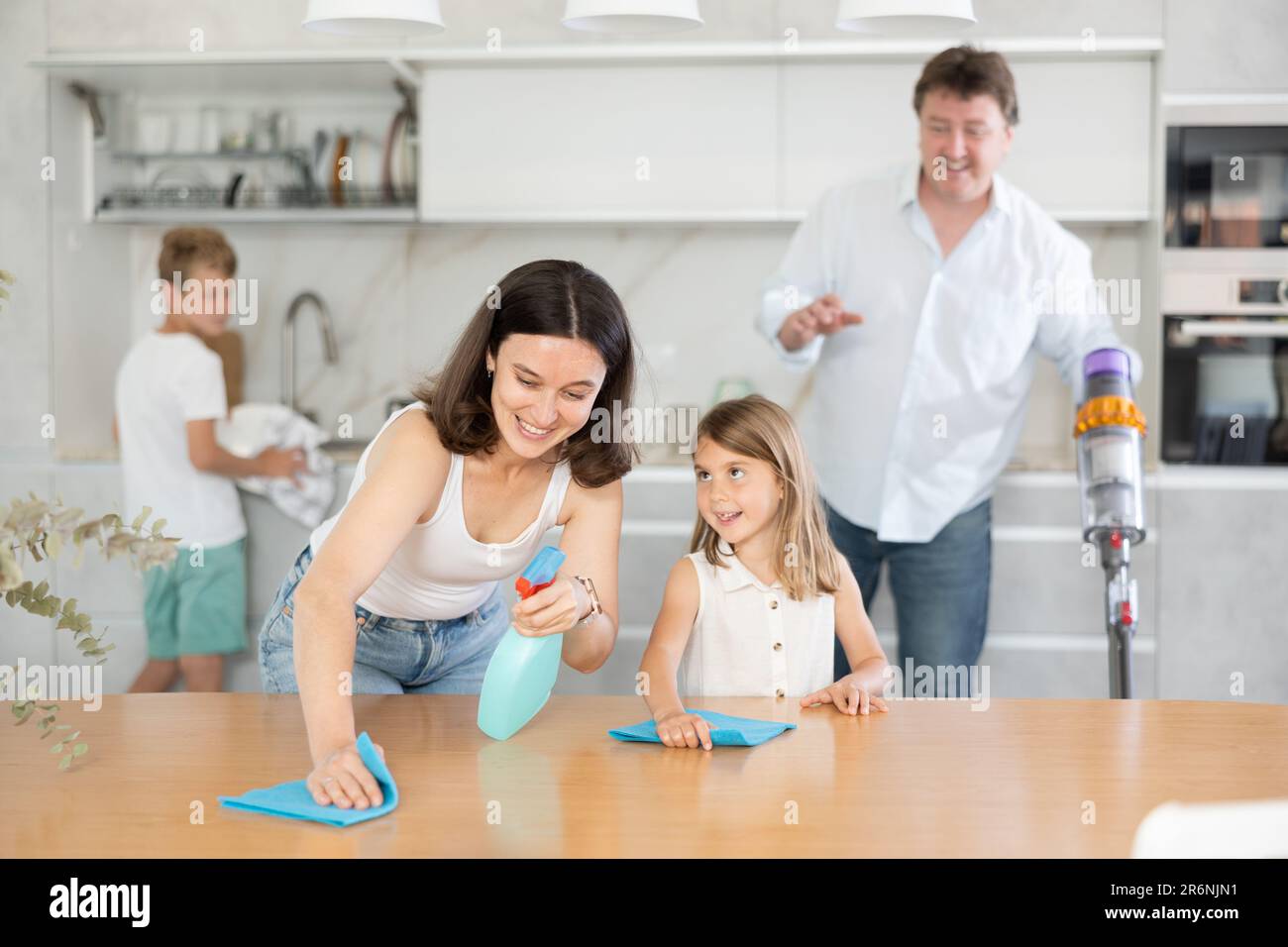 Mom and little daughter are dusting the table. Father and son cleaning ...