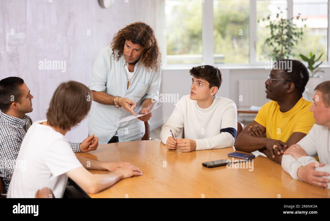 Man conducting meeting with male colleagues around table Stock Photo ...