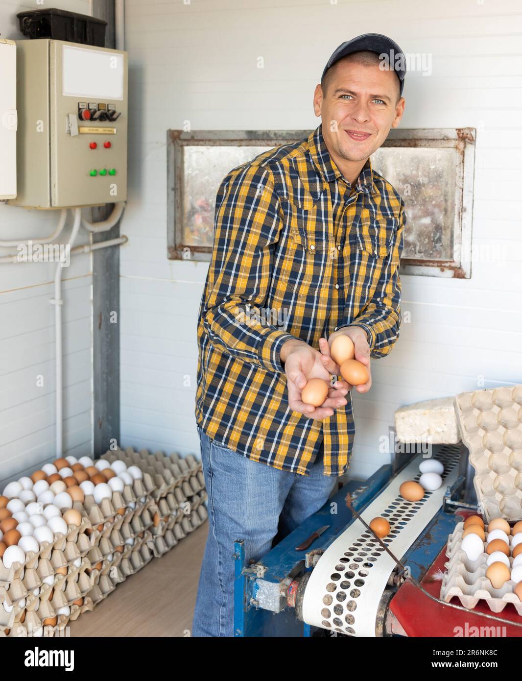 Positive young male farmer worker sorting and labeling chicken eggs on ...