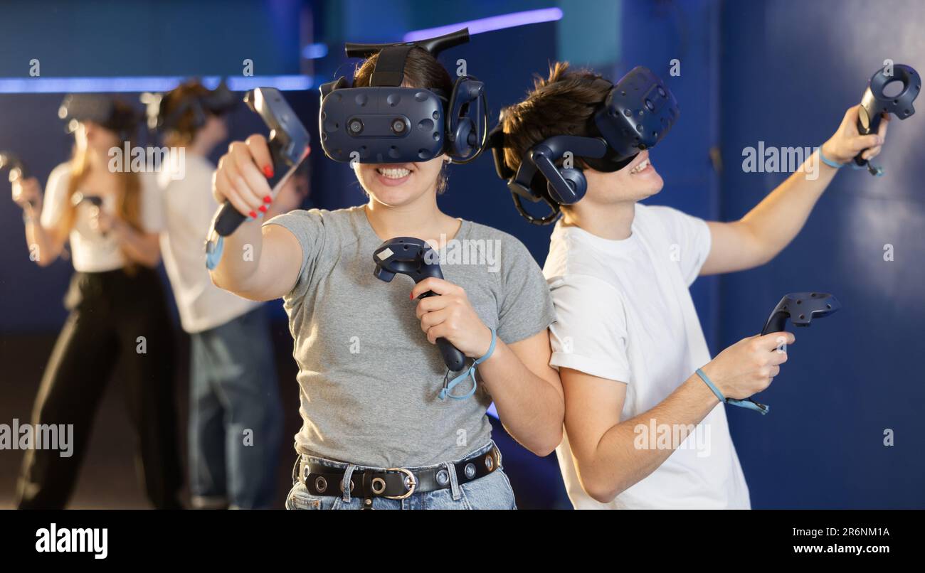 Young guy and girl in vr headset stand shoulder to shoulder interacting ...
