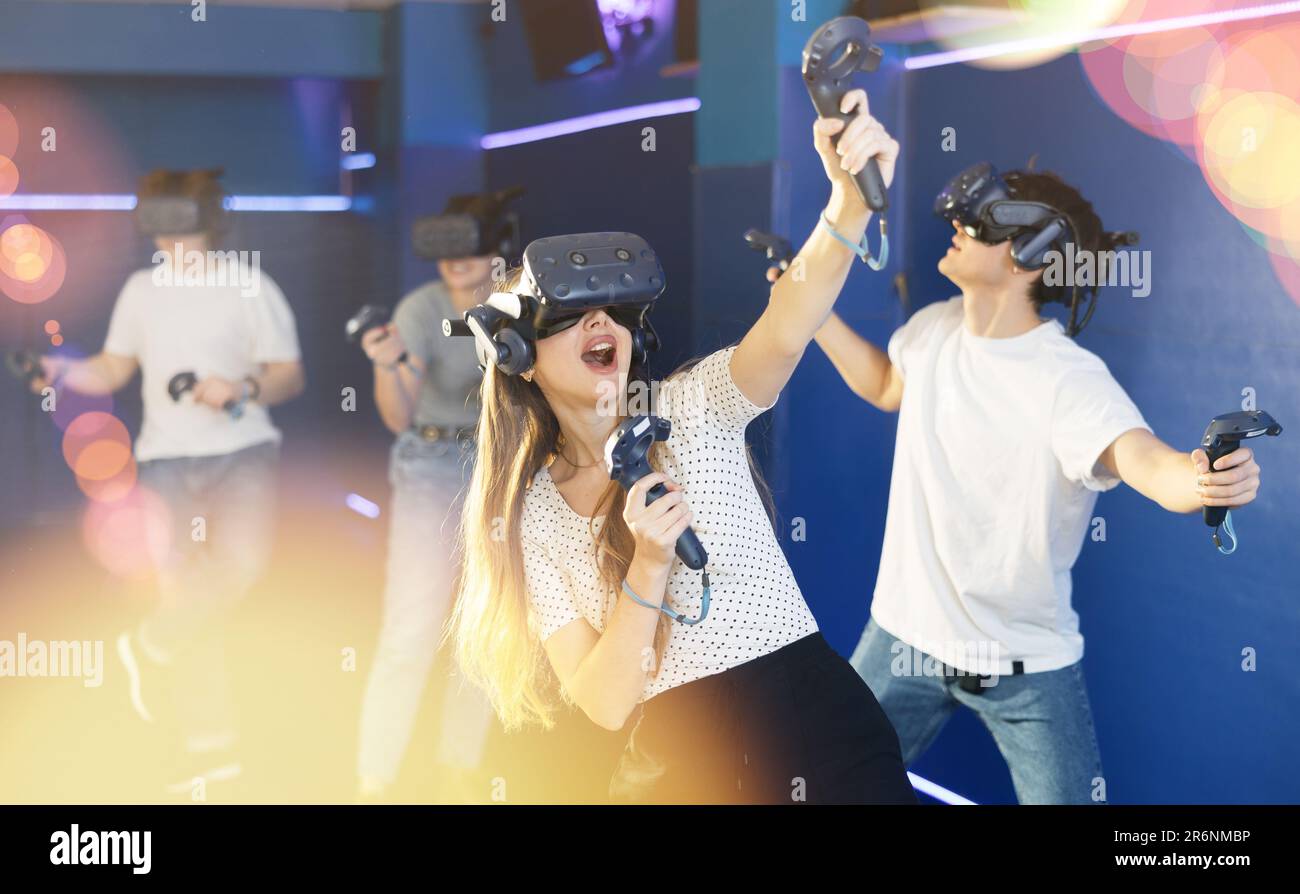 Two teenagers in virtual reality glasses with joysticks play survival ...