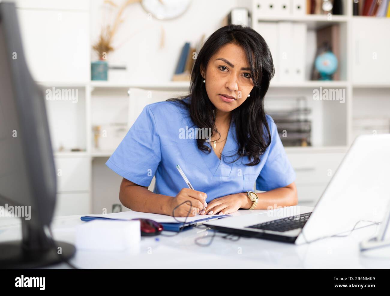 Nurse working on PC in modern private clinic with white walls Stock ...