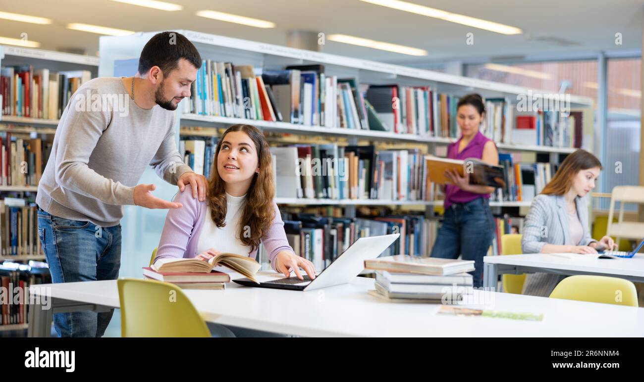 Man recommending books to woman in public library Stock Photo - Alamy