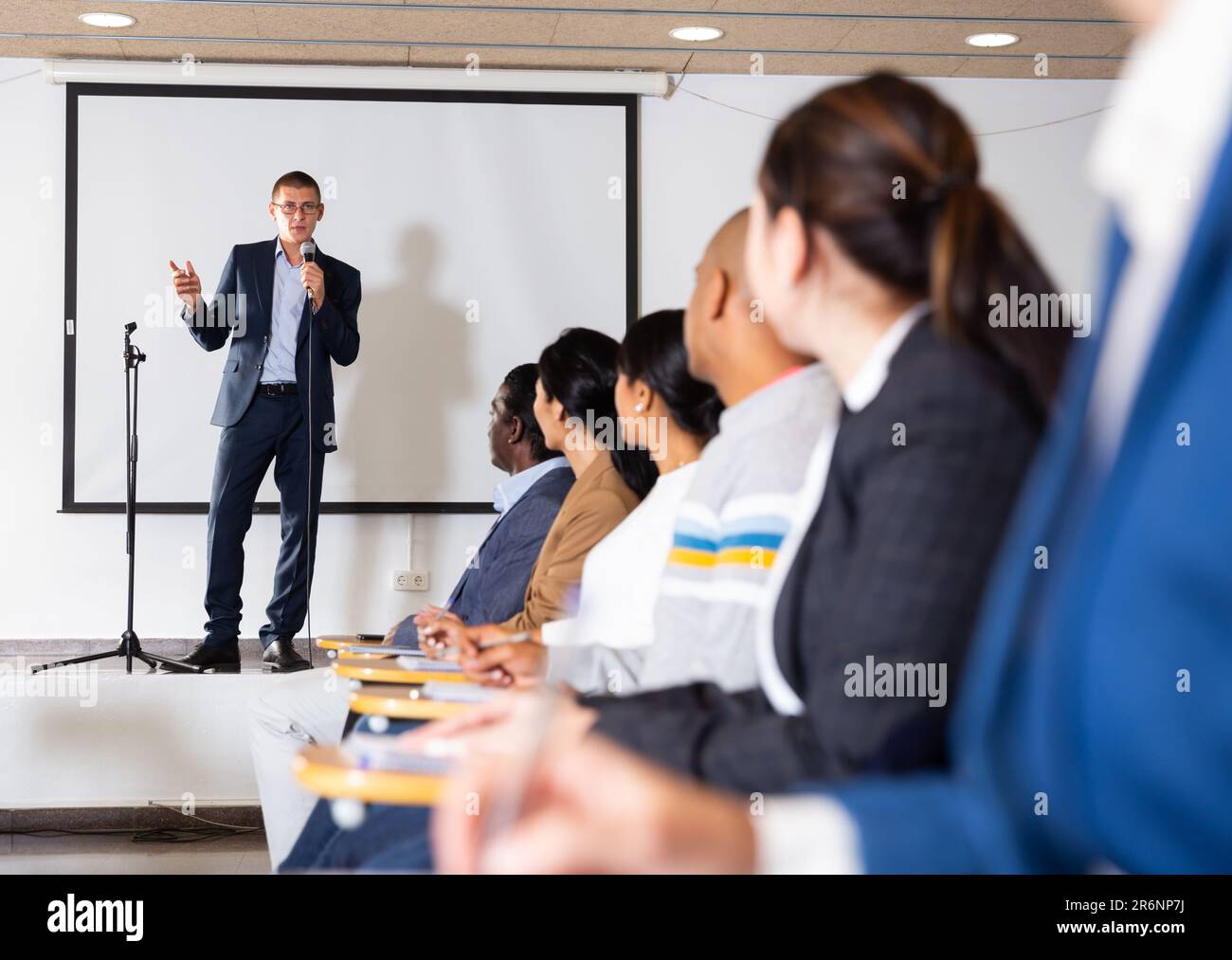 Business coach speaking from stage to audience at corporate training ...