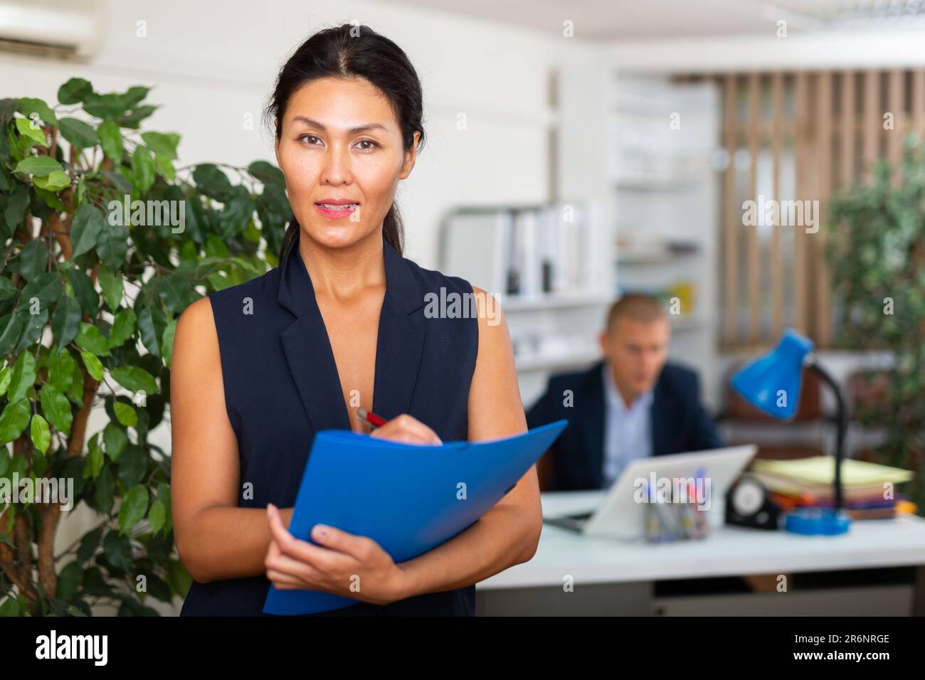 Female administrative secretary standing in office with folder of ...