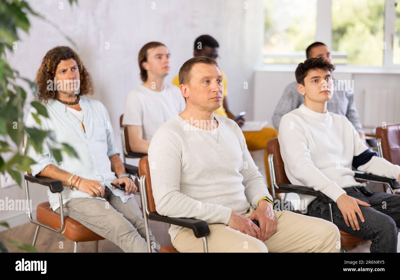 Adult male student listening to lecture with group of men Stock Photo ...