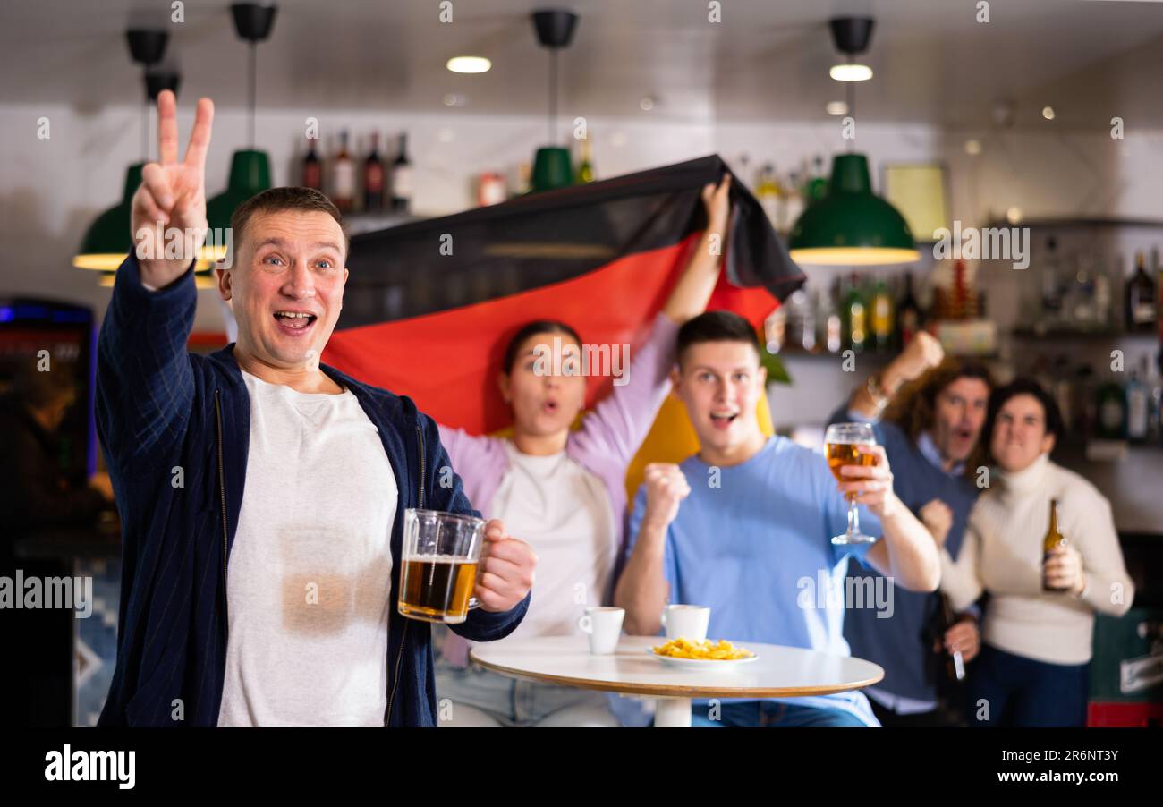 Company of emotional young adult fans supporting German team with state ...
