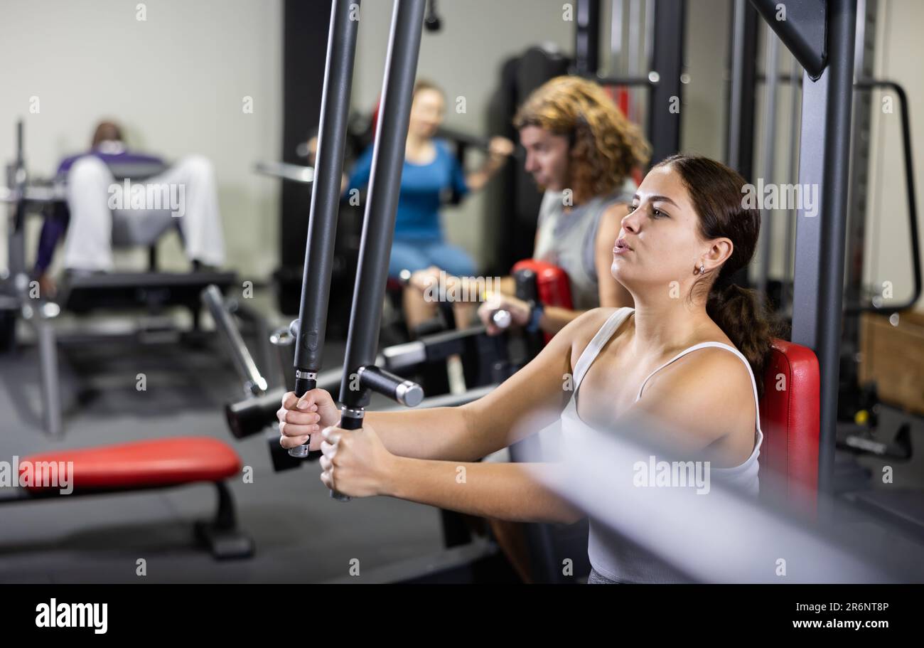 Sporty woman works on special simulator for development of pectoral ...