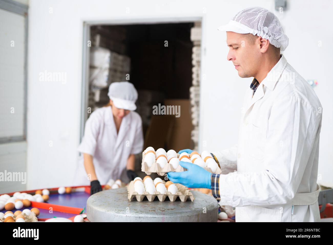 group of people in lab coats and hairnets doing egg quality control in ...