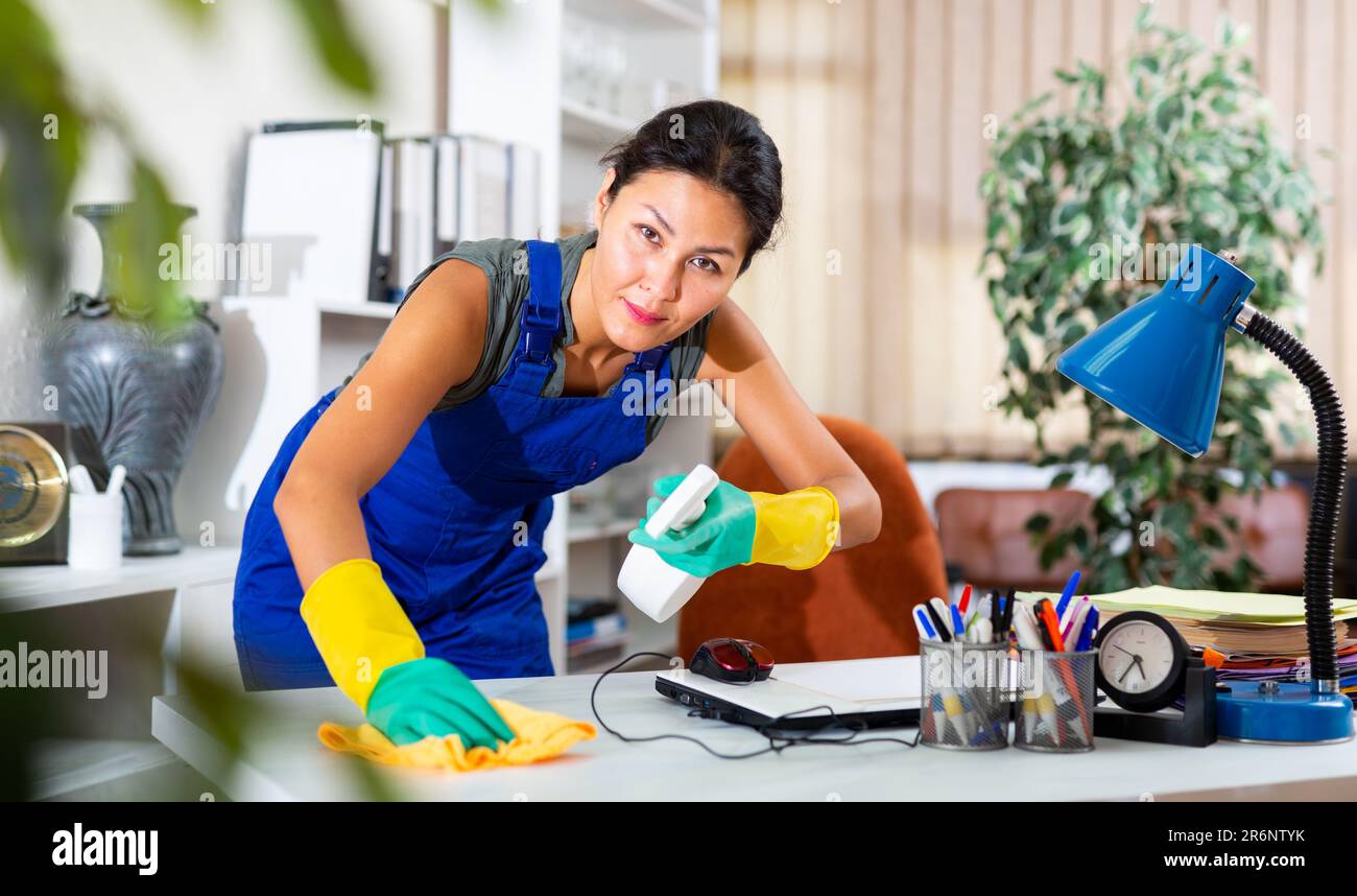Woman cleans up desktop in office with rag and cleaning products Stock ...