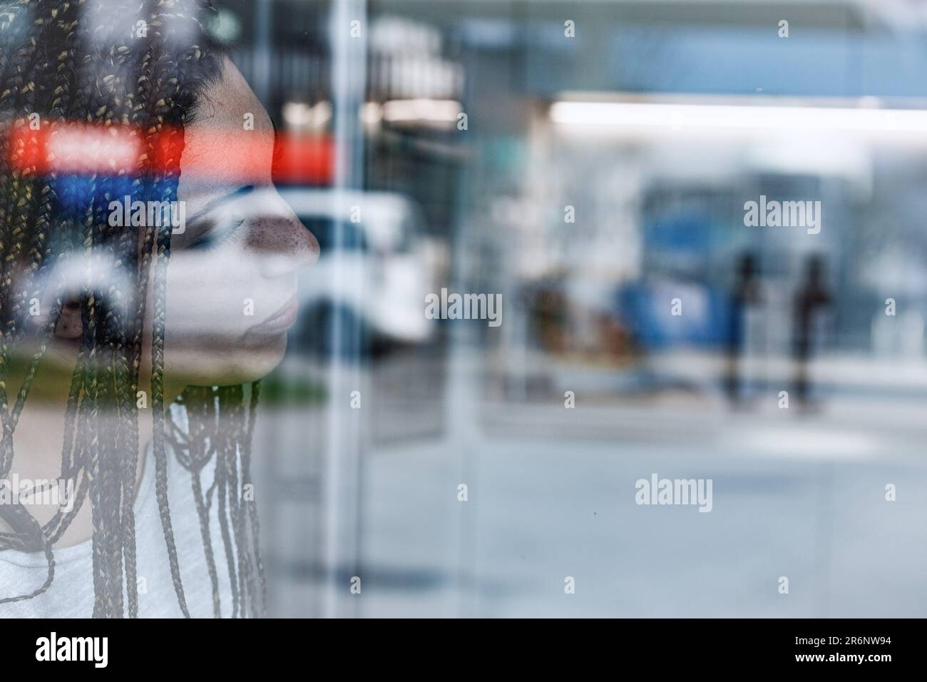 Boxbraids woman against a window reflecting outdoors. Barely visible ...
