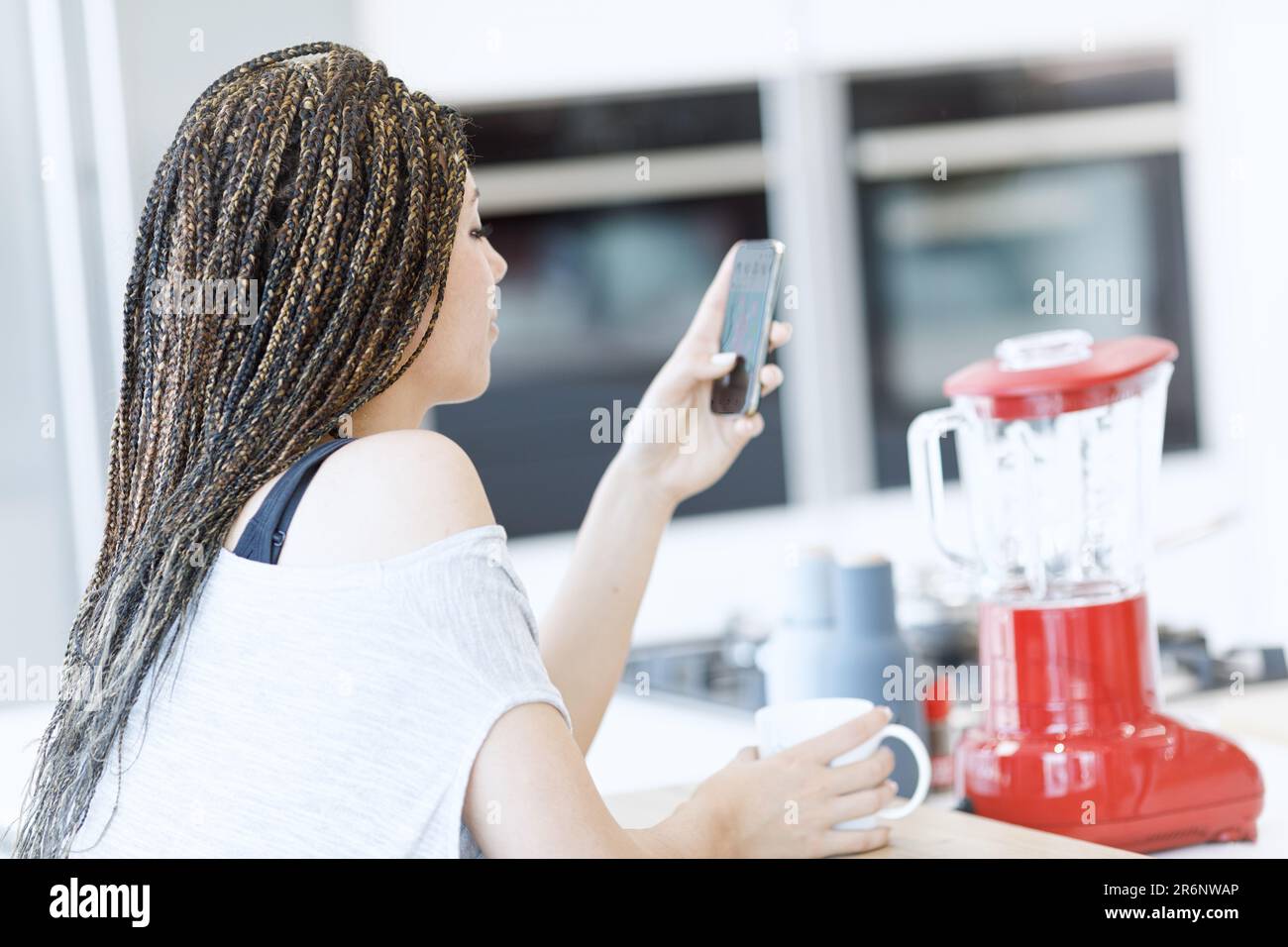 In her spacious kitchen, a young woman with box braids uses her ...