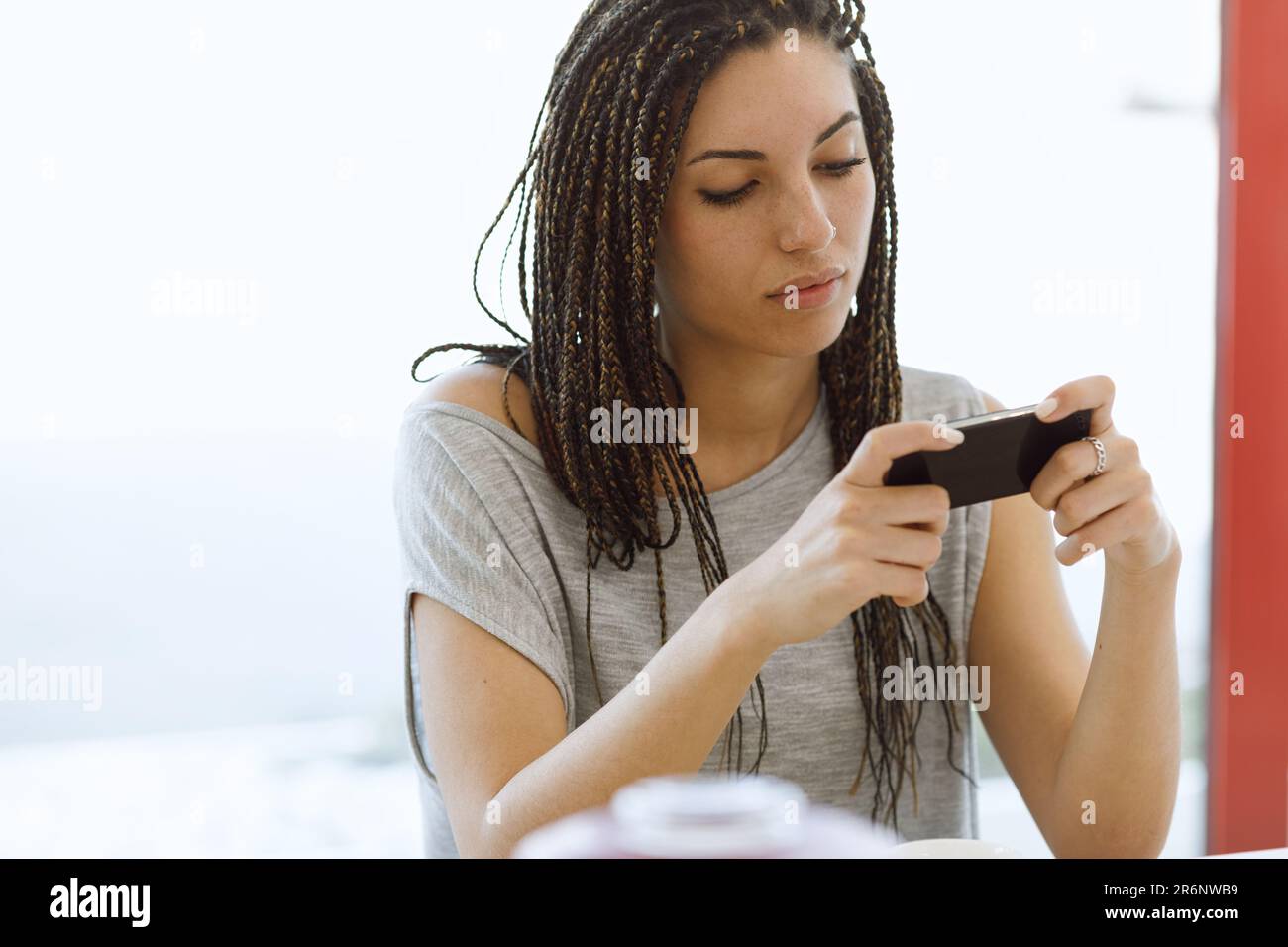 A young lady uses her smartphone in her kitchen for work and study ...