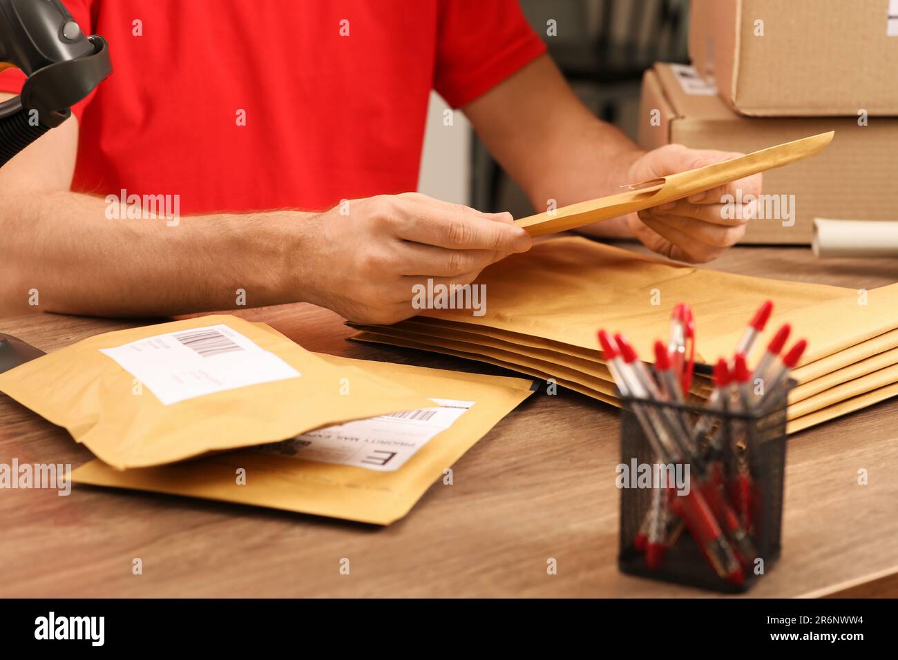 Post office worker with adhesive paper bags at counter indoors, closeup ...