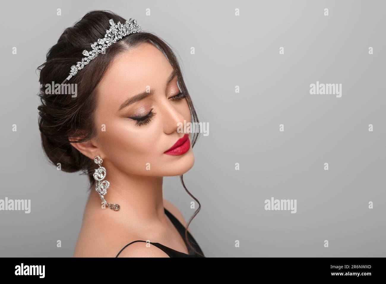 Beautiful young woman wearing luxurious tiara on light grey background ...